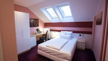 Quarto com cama, escrivaninha, cadeira e claraboias.