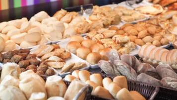Diversos produtos de panificação, como pão, bolos e biscoitos, expostos em bandejas.