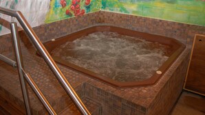 Uma banheira de hidromassagem com revestimento de azulejos e um mural colorido ao fundo.