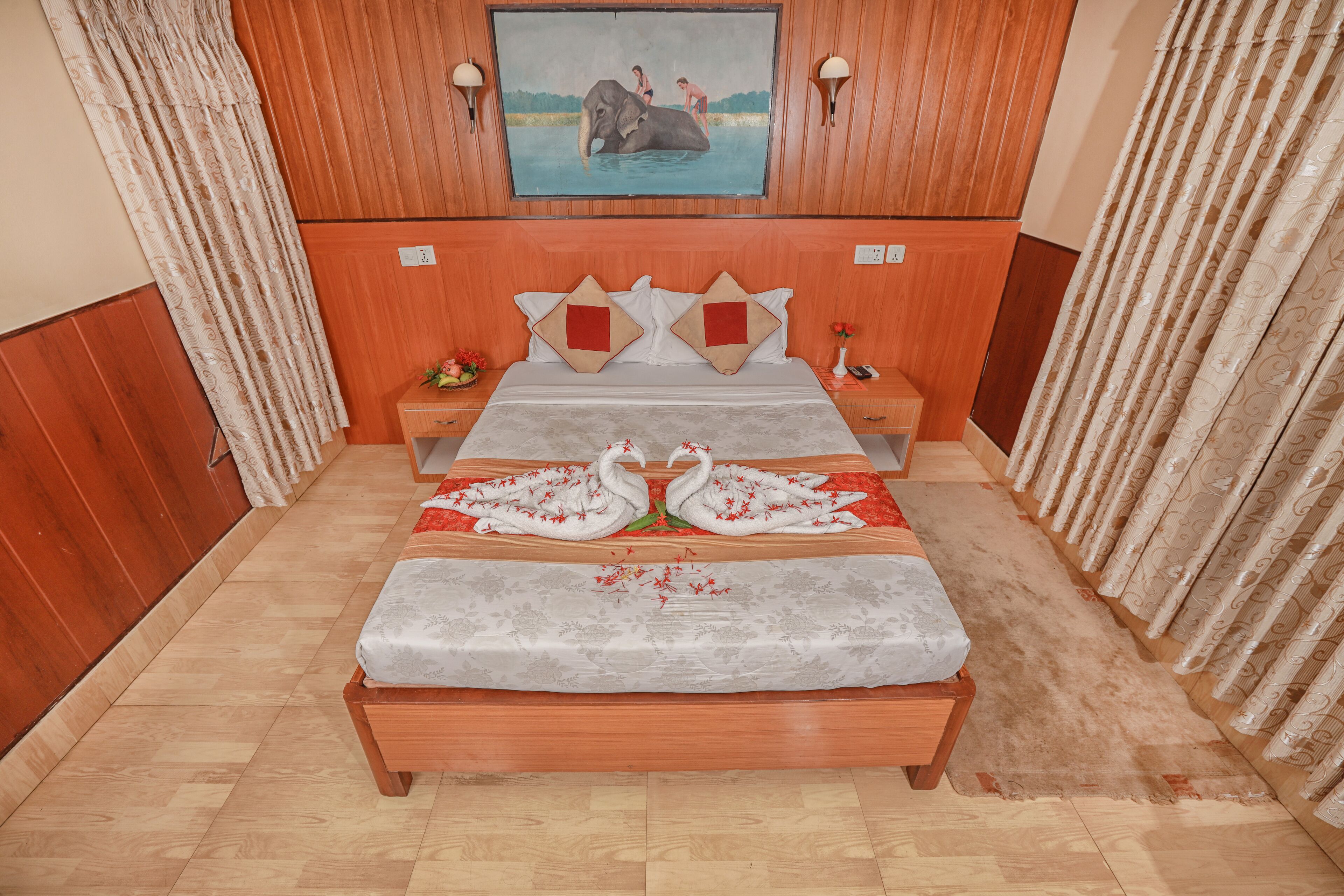 Quarto de hotel com cabeceira de madeira, um quadro sobre a cama e uma cama decorada com o desenho de um cisne.
