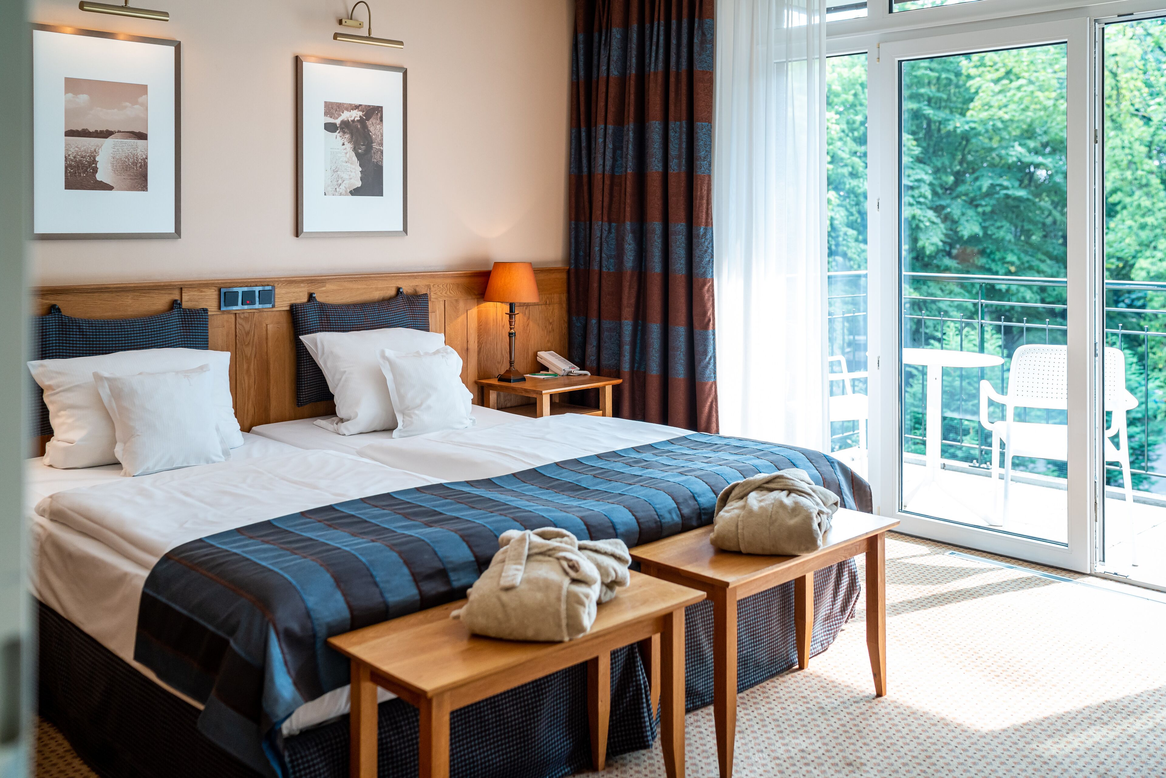 Quarto de hotel com uma cama grande, duas mesas de cabeceira e uma varanda com uma cadeira.