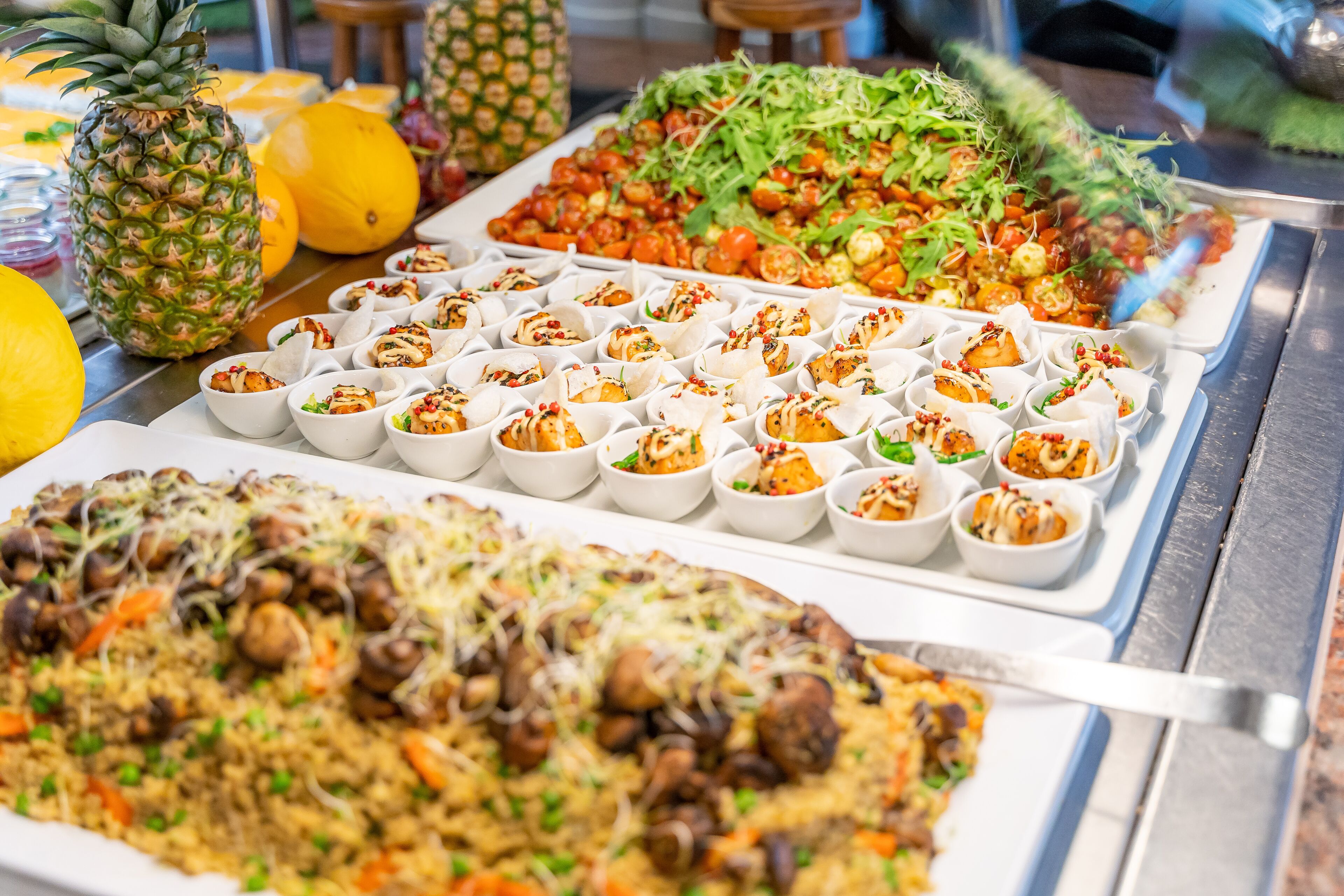 Buffet com diversos pratos, incluindo uma grande travessa de arroz, pequenas porções de aperitivos e um monte de vegetais.