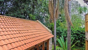 Um edifício com telhado de telhas vermelhas, cercado por vegetação exuberante e altas palmeiras.