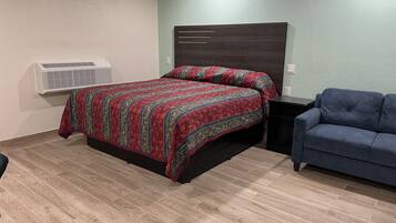 Quarto com cama, sofá azul e ar-condicionado fixado na parede.