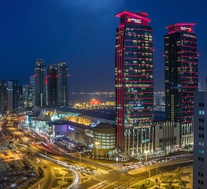 Um hotel alto com uma placa grande 'Marriott', situado em um ambiente urbano movimentado, com tráfego visível e outros edifícios.