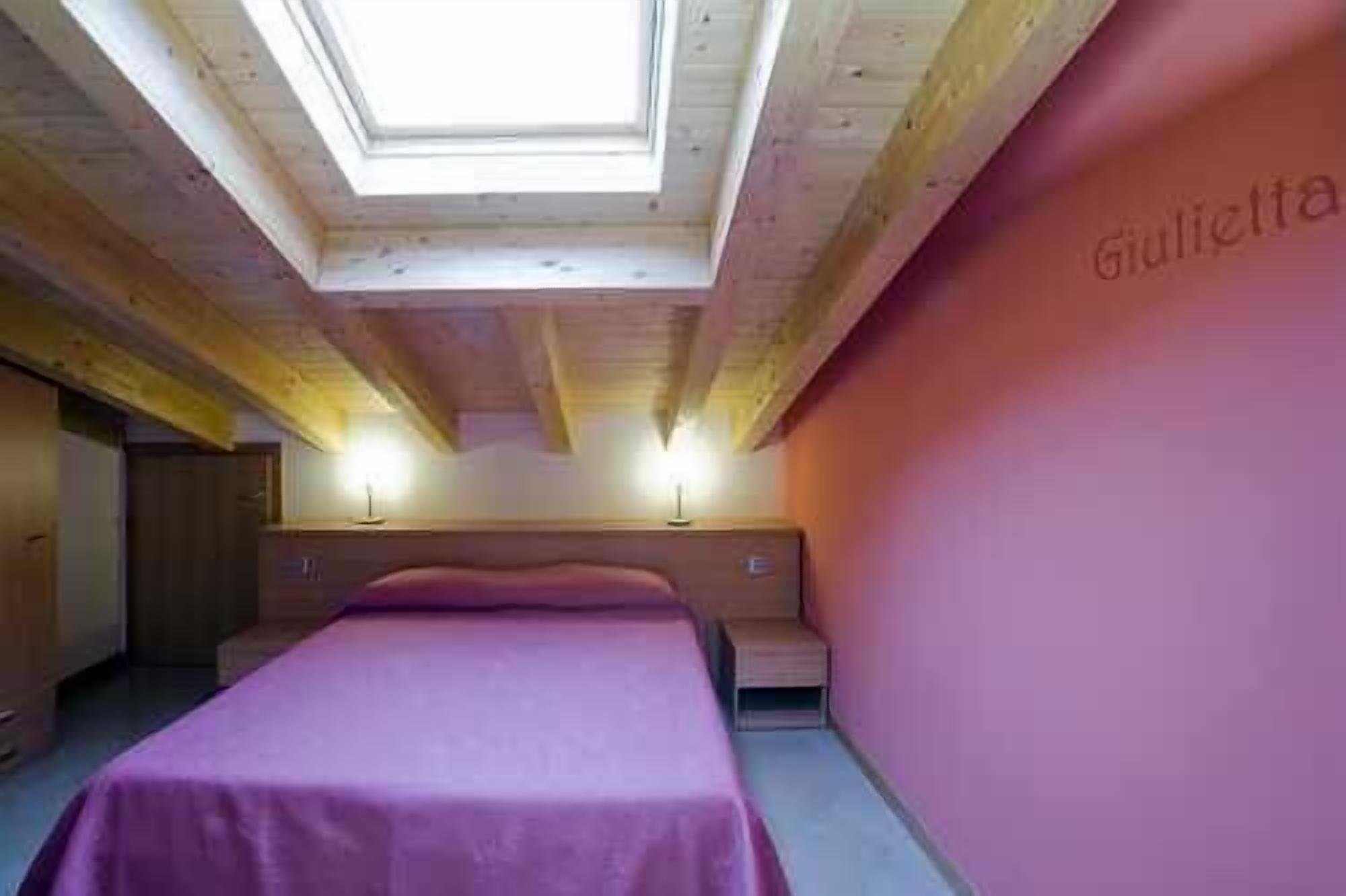 Quarto com claraboia, cama e mesa de cabeceira.