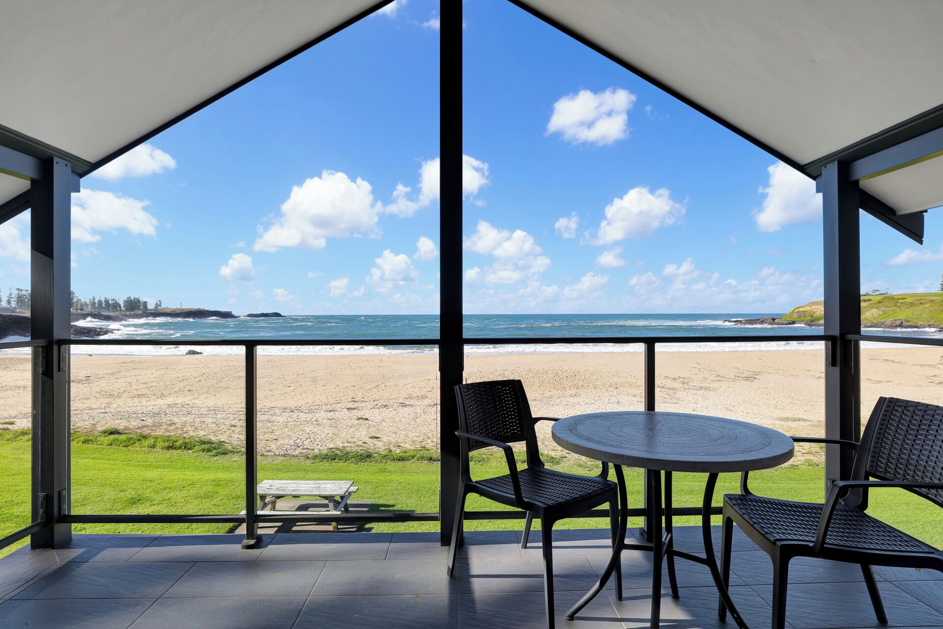 Uma área de estar coberta ao ar livre, com vista para a praia e o oceano.