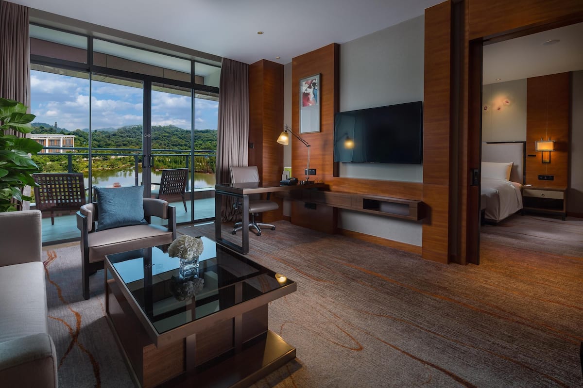 Quarto de hotel moderno com uma varanda ampla, televisão de tela plana, sofá, mesa de centro e área de trabalho.