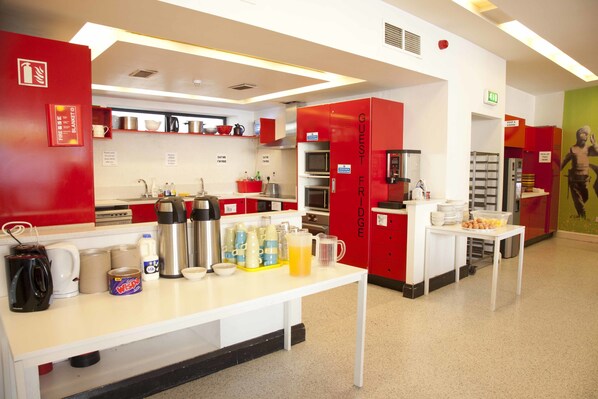 Cozinha moderna com detalhes em vermelho, equipada com cafeteira, chaleiras e micro-ondas.