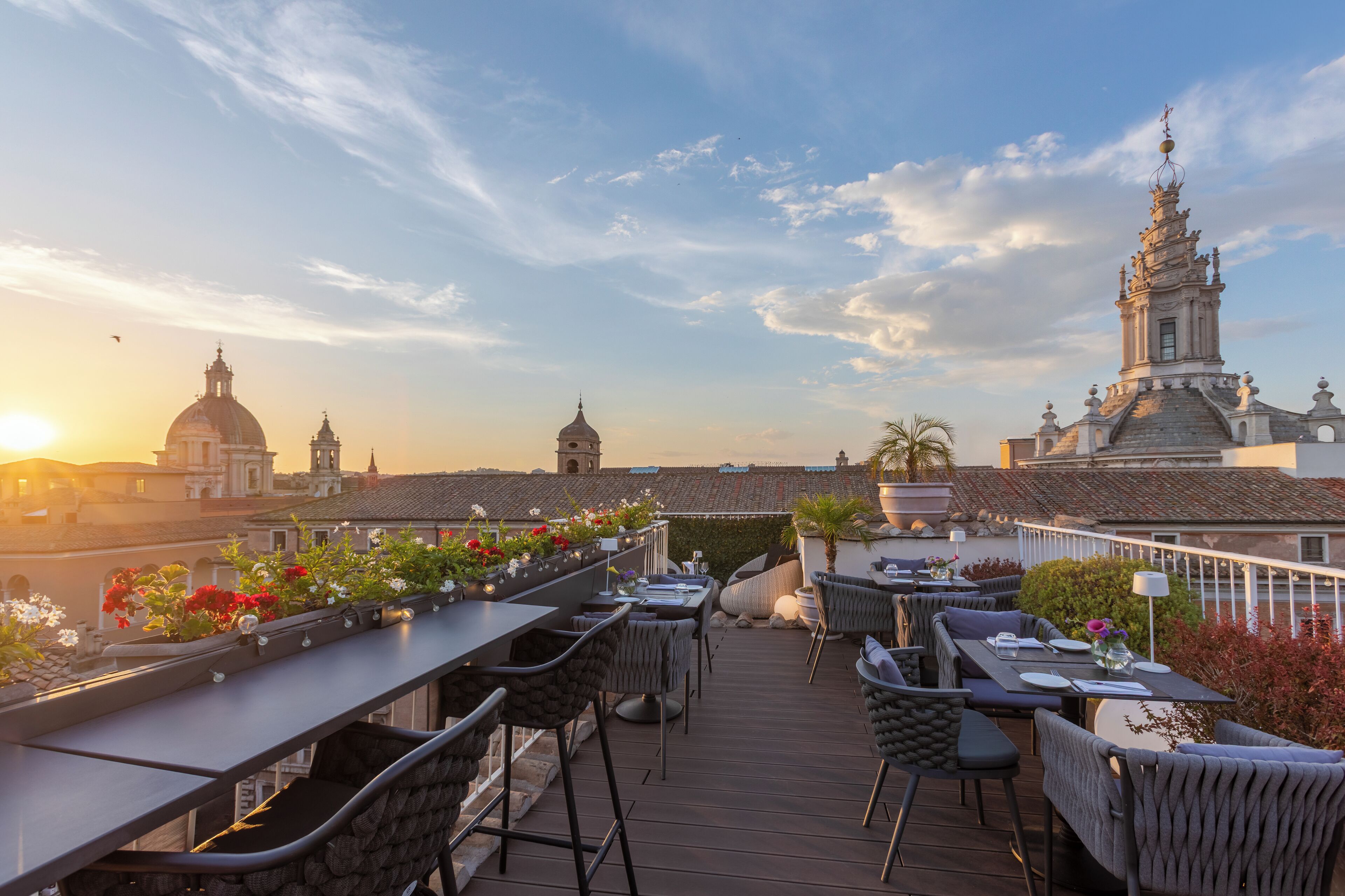 Terraço ao ar livre com mesas e cadeiras, com vista para um centro histórico com edifícios em cúpula.