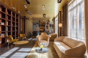 Um lobby moderno com sofás de couro, uma mesa de centro e uma estante de livros.