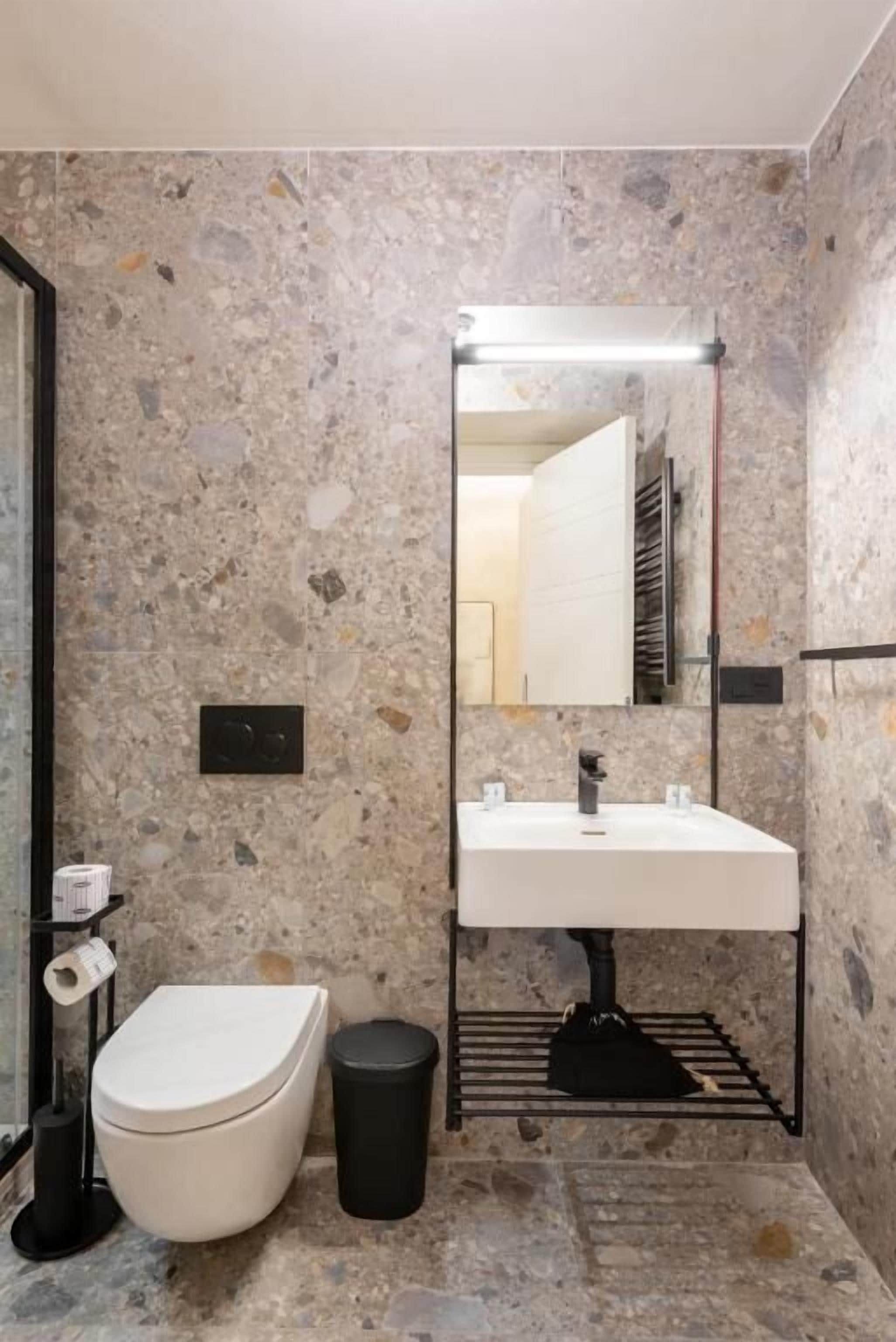 Uma casa de banho moderna com sanita branca, lavatório e espelho.