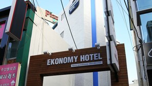 Entrada do Hotel Economy, com uma placa anunciando a inauguração.