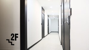 Corredor moderno com portas em ambos os lados, piso ladrilhado e uma placa indicando a sala 2F.