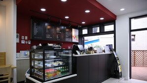 Interior moderno de café com uma vitrine refrigerada, um quadro de menu e uma área de estar.