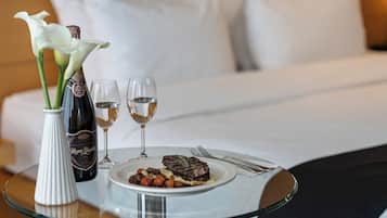 Uma mesa de jantar com uma garrafa de vinho, duas taças, um prato de comida e um vaso com flores.