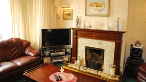 Uma sala de estar com sofá de couro, TV de tela plana, lareira e manto decorativo.