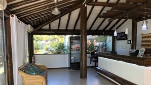 Uma área de recepção com uma cadeira de vime, um balcão e vista para o exterior.
