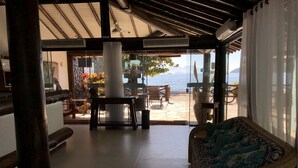Quarto espaçoso com vista para o mar, um sofá de vime, uma mesa e uma cadeira.