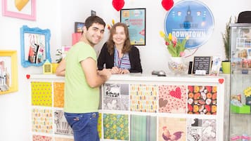 Uma receção com vários exemplos de tecidos coloridos e um letreiro para o Warsaw Downtown Hostel.