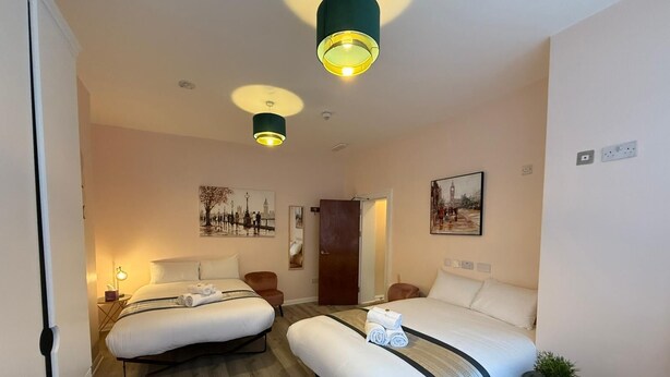 Quarto de hotel com duas camas, piso de madeira e obras de arte nas paredes.