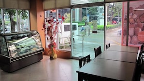 Interior de restaurante com uma vitrine de vidro, uma mesa de jantar e cadeiras.