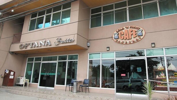 Um edifício com um café chamado "Cafe N Fresh" e uma placa indicando "Oftana Suites".
