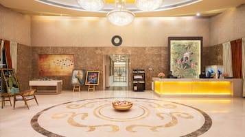 Um hall com mesa de recepção, uma pintura grande, um relógio e uma tigela decorativa no centro.