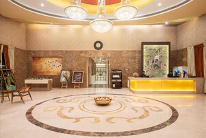 Um hall com mesa de recepção, uma pintura grande, um relógio e uma tigela decorativa no centro.
