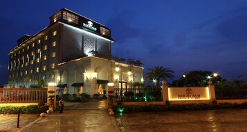Hotel com placa visível, entrada bem iluminada e acesso por portão.