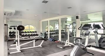 Uma academia com equipamentos de musculação, esteiras e espelhos.