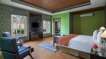 Quarto com cama grande, televisão, escrivaninha e cadeira.