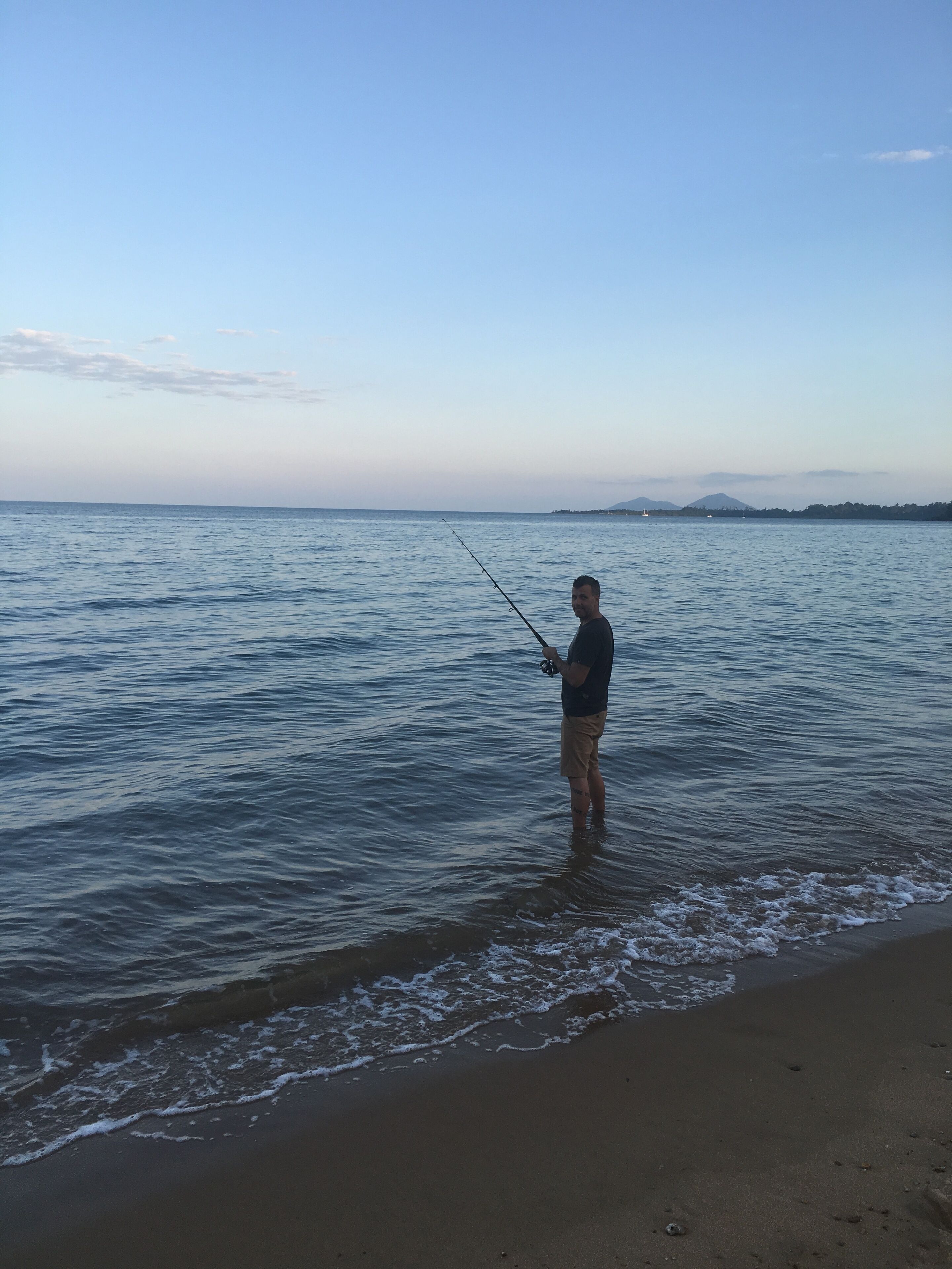 Uma pessoa em águas rasas segurando uma vara de pesca.