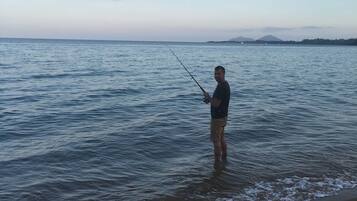 Uma pessoa em águas rasas segurando uma vara de pesca.