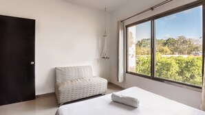 Um quarto moderno com uma janela ampla, uma cama, um sofá e um lustre.