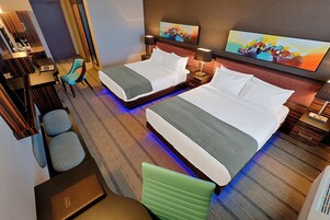Quarto de hotel com duas camas, uma escrivaninha e uma cadeira.