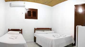 Quarto pequeno e limpo com duas camas de solteiro, teto de madeira, ar condicionado e uma janela.