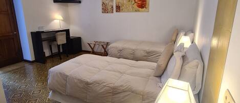 Quarto com cama, escrivaninha, cadeira, ventilador de teto e televisão.