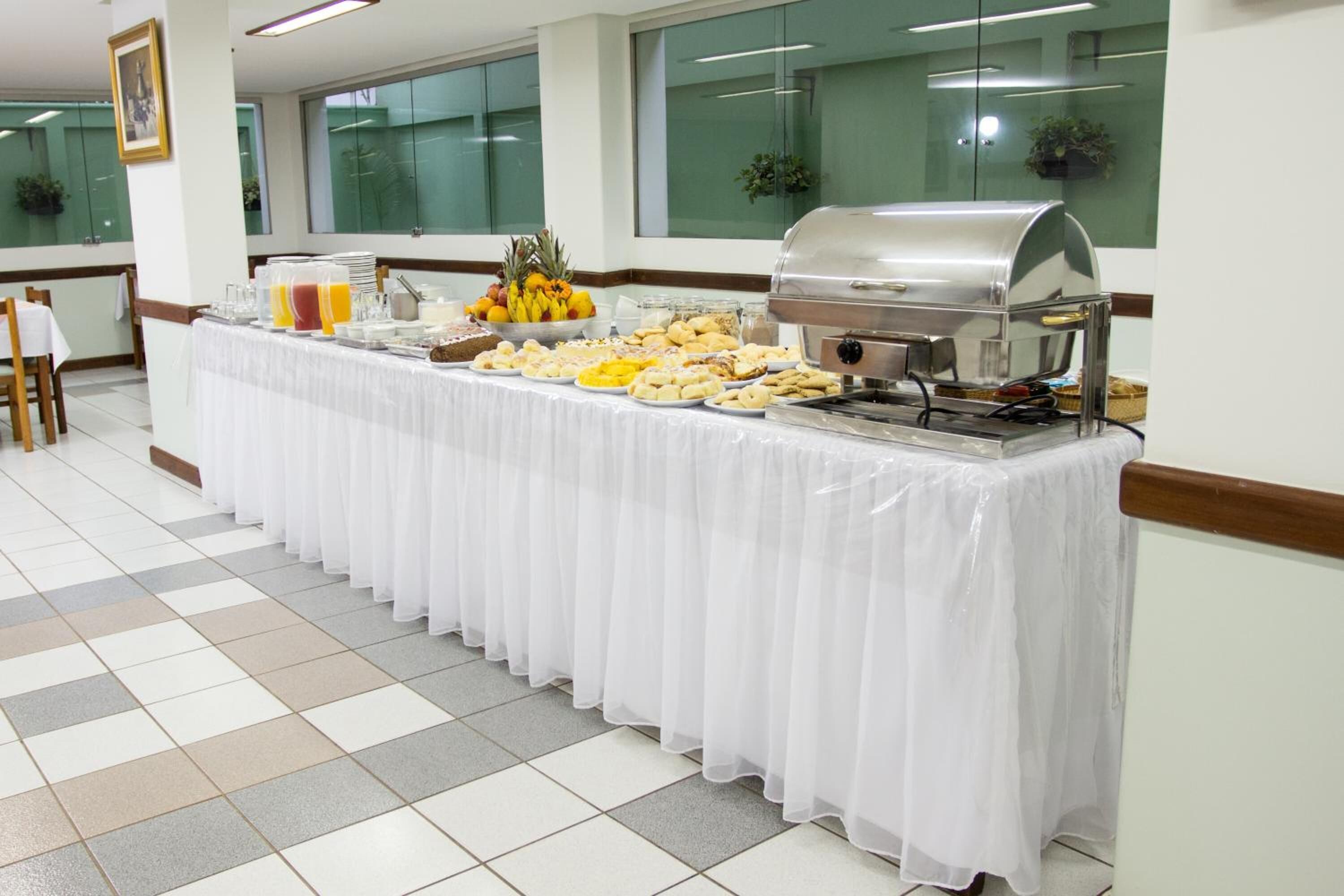 Disposição de buffet com diversos pratos e um espaço para bebidas de serviço por conta própria.