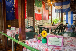 Restaurante com mesas preparadas para refeições, exibindo bandeiras de diversos países e um aviso sobre uma oferta especial.