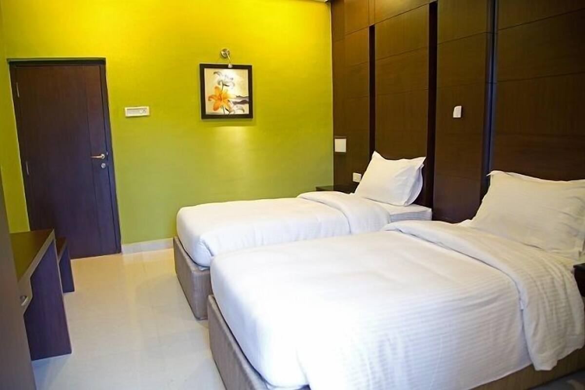 Quarto de hotel com duas camas, uma mesa e uma porta.