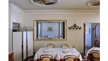 Uma sala de jantar com uma mesa posta para quatro pessoas, um espelho acima da mesa e um objeto decorativo na parede.