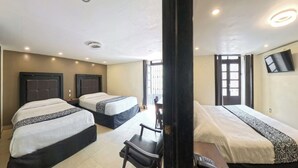 Quarto de hotel com duas camas, uma mesa, uma cadeira, uma TV e uma janela com cortinas.