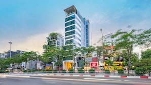 Um hotel moderno com fachada de vidro marcante, terraço no terraço e área de jardim bem cuidada.
