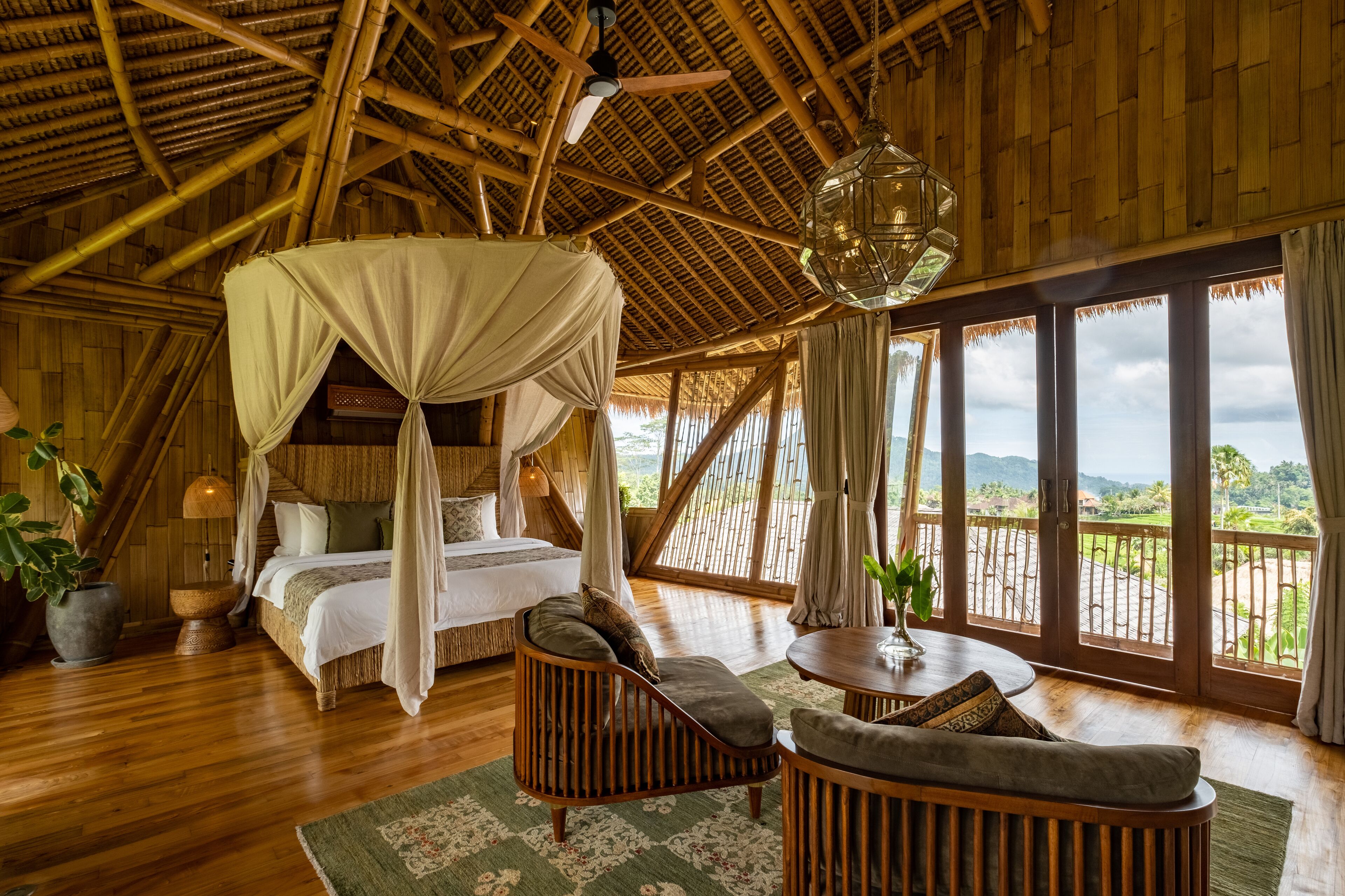 Um quarto espaçoso com cama de dossel, um espaço de estar com mesa redonda e grandes janelas com vista para a paisagem.