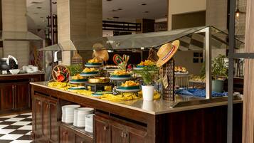 Disposição de buffet com diversos alimentos e um chapéu decorativo.