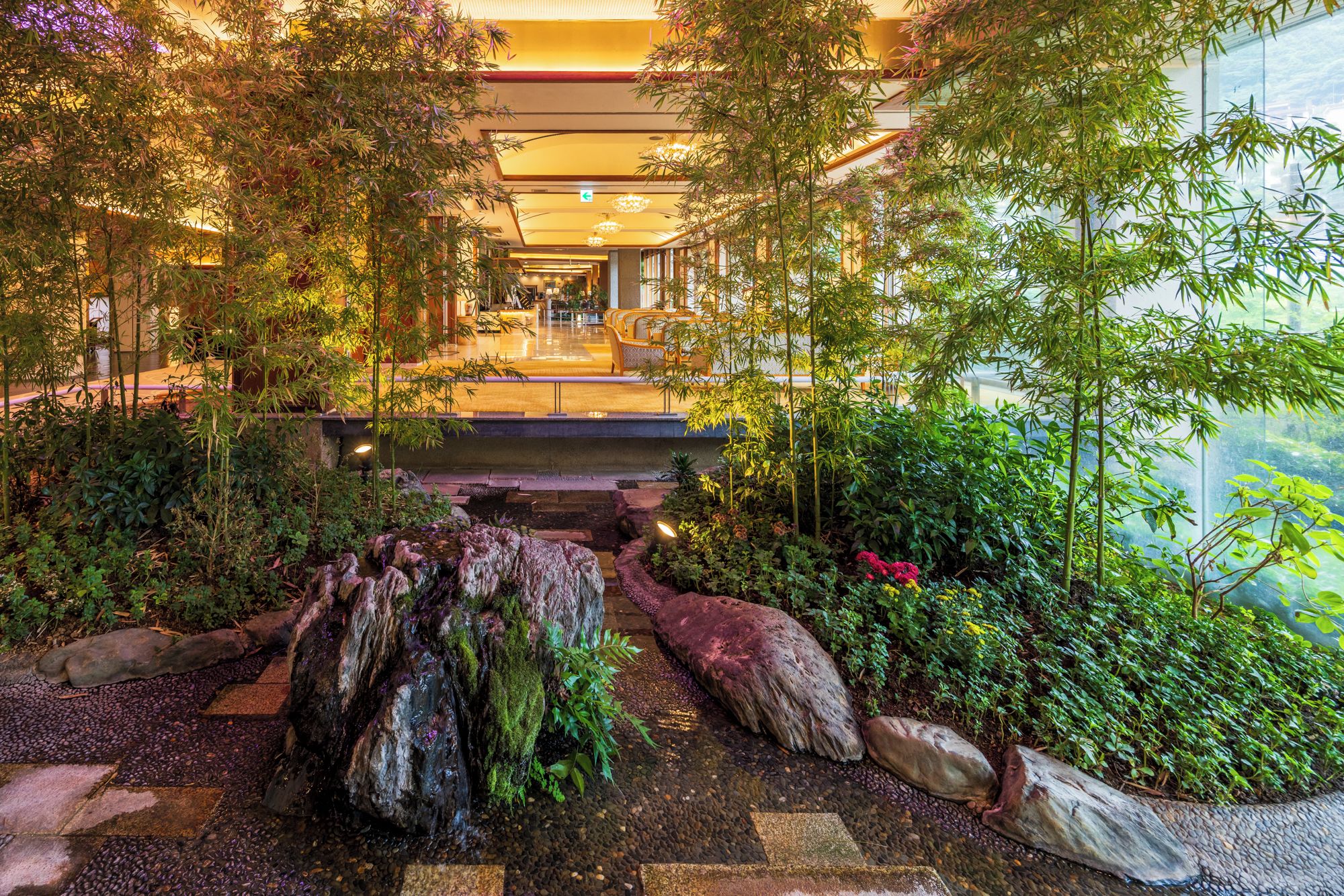 Jardim interno com fonte, área de estar e vista para o exterior.