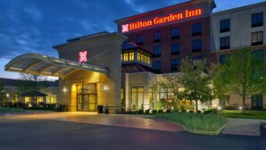 Um Hilton Garden Inn com entrada desobstruída, uma placa grande e fachada bem iluminada.