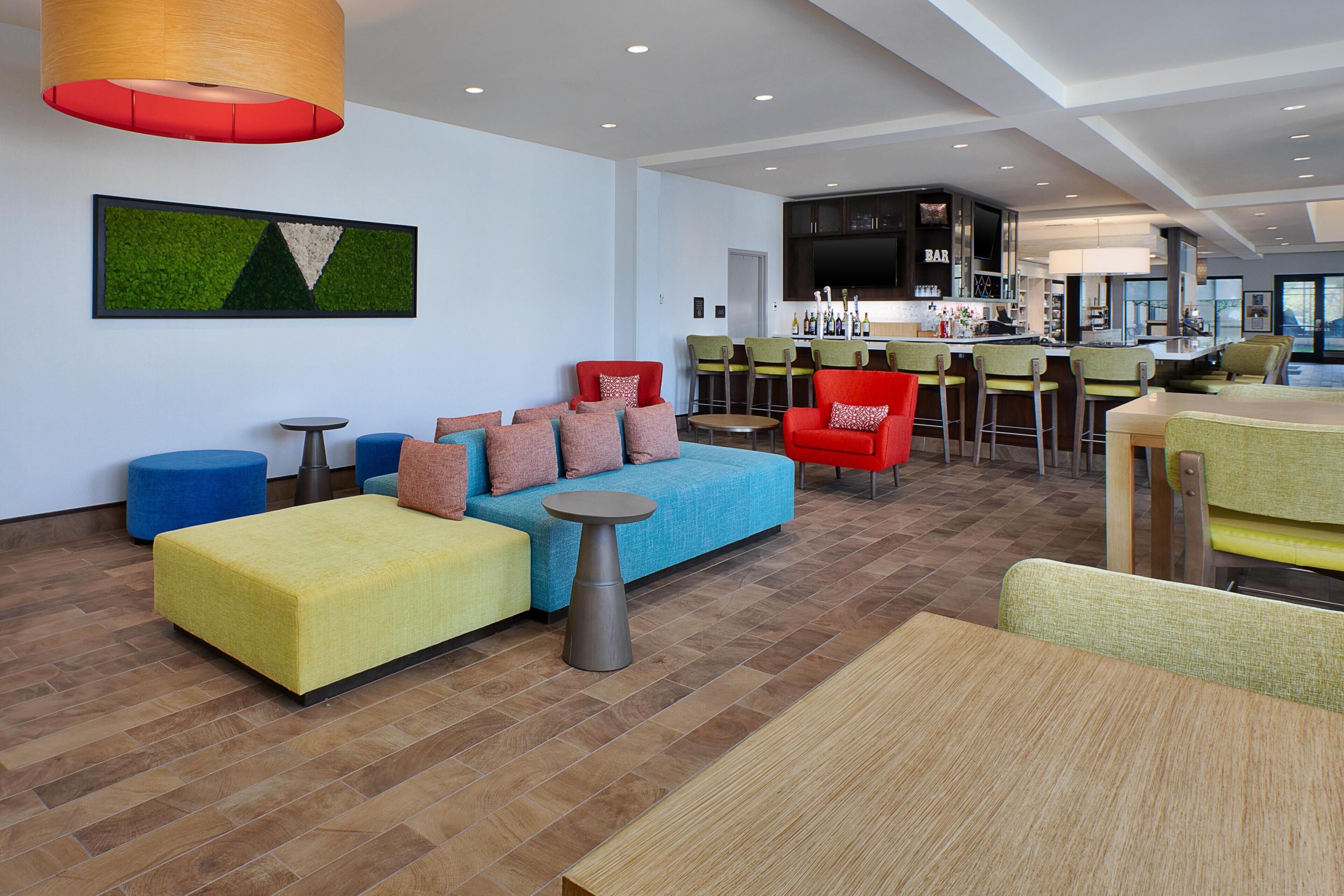 Uma sala de estar moderna com sofá, apoio para os pés, cadeiras e um espaço de bar.