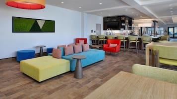Uma sala de estar moderna com sofá, apoio para os pés, cadeiras e um espaço de bar.
